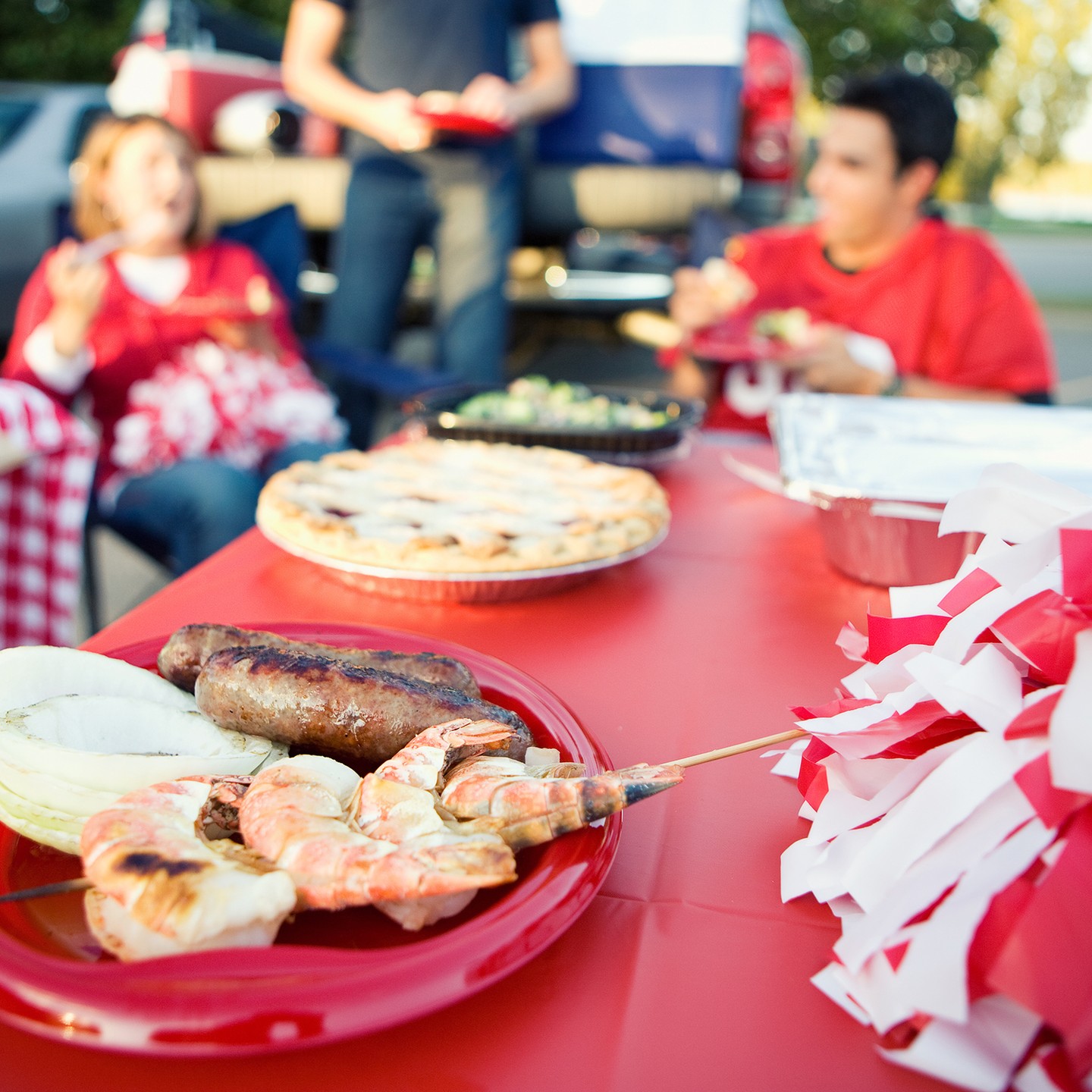Group of friends doing football tailgating. Cooking food, cheering, etc.